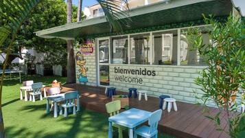 Uma área de recreação infantil com uma placa que diz 'bienvenidos welcome' e um personagem de desenho animado.