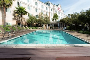 Uma área de piscina de hotel com espreguiçadeiras e uma piscina azul límpida.