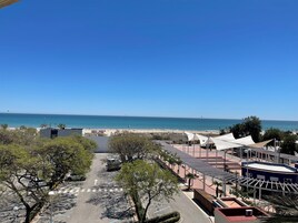 Vista costeira com praia, área de estacionamento e edifícios.