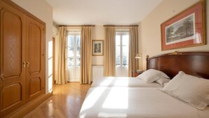 Quarto de hotel com uma cama grande, armário de madeira e uma pintura na parede.