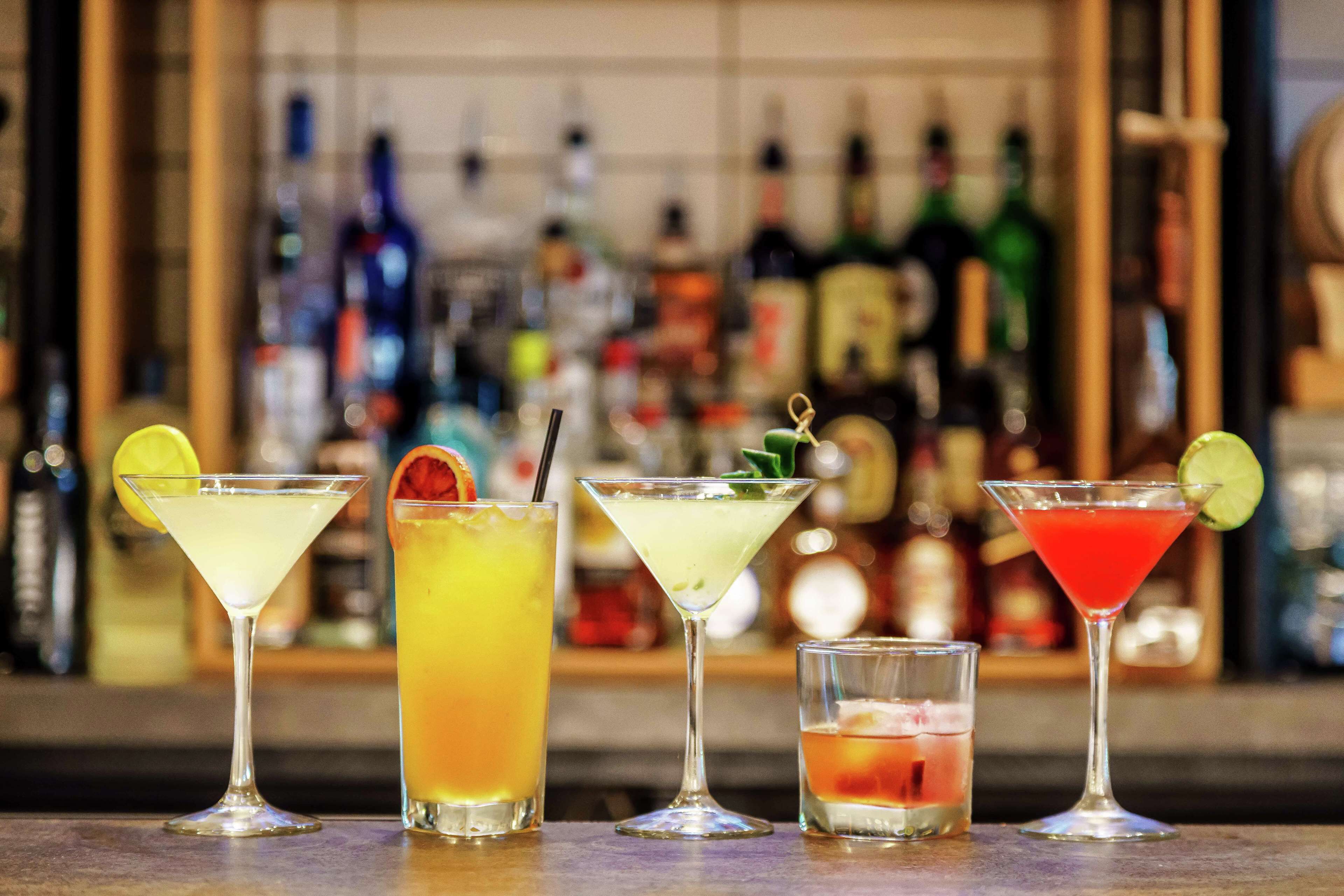 Um bar com cinco coquetéis diferentes, cada um com um guarnição única.