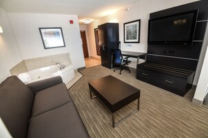Quarto de hotel moderno com sofá, TV de tela plana, escrivaninha e uma janela grande.