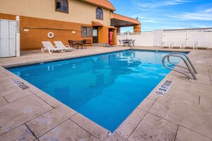 Piscina com espreguiçadeiras e uma máquina de vendas vermelha.