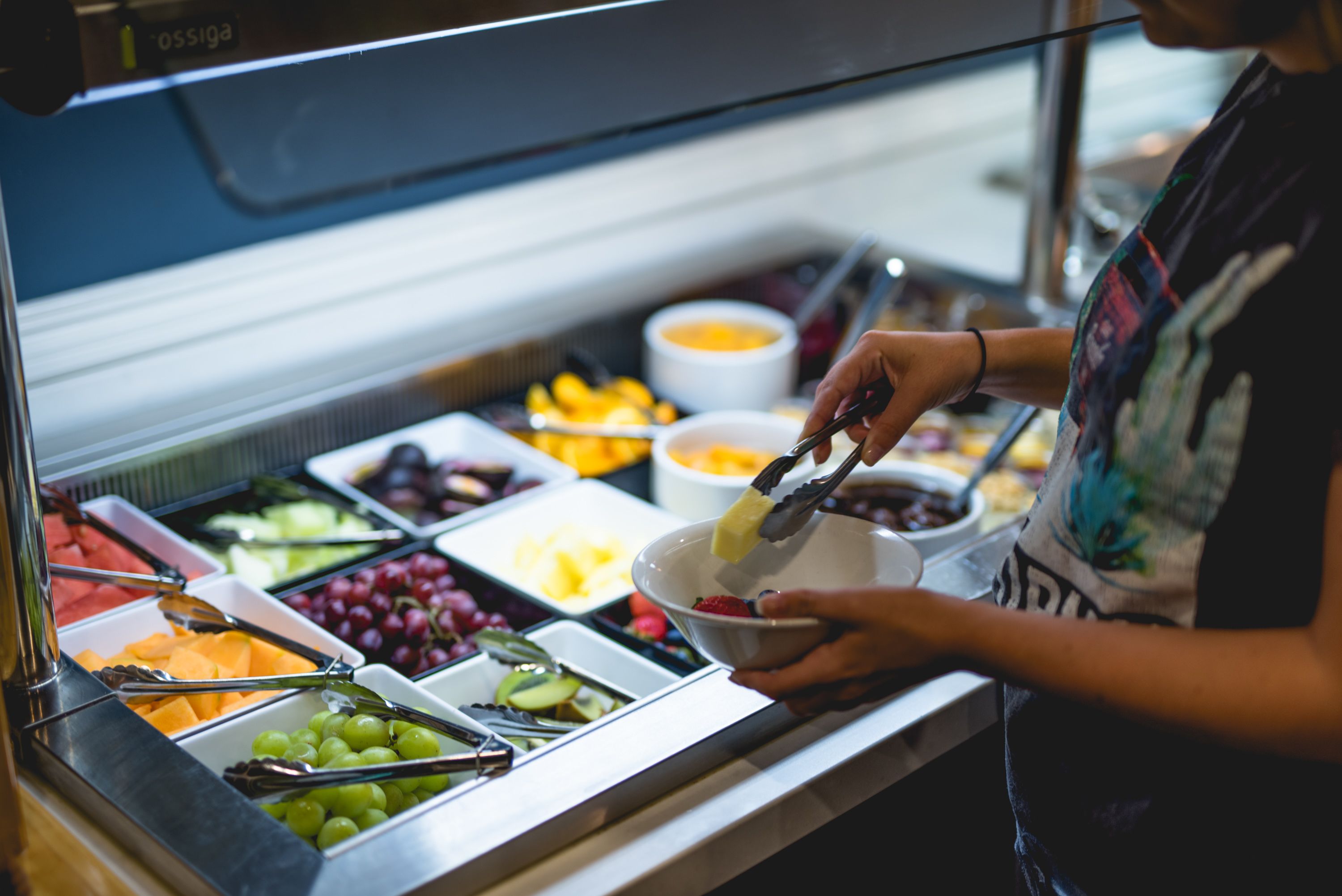 Buffet com diversos alimentos, incluindo frutas, legumes e uma tigela de sopa.
