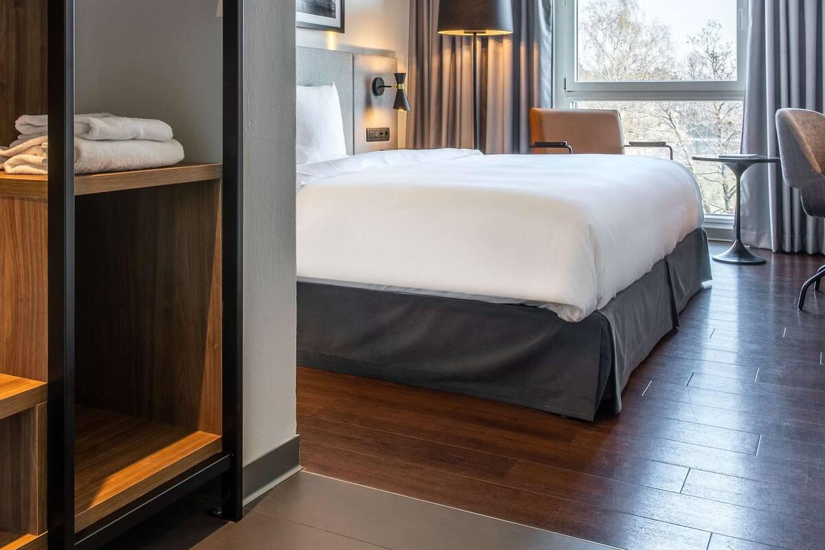 Quarto de hotel moderno com uma cama grande, uma escrivaninha e um guarda-roupa.