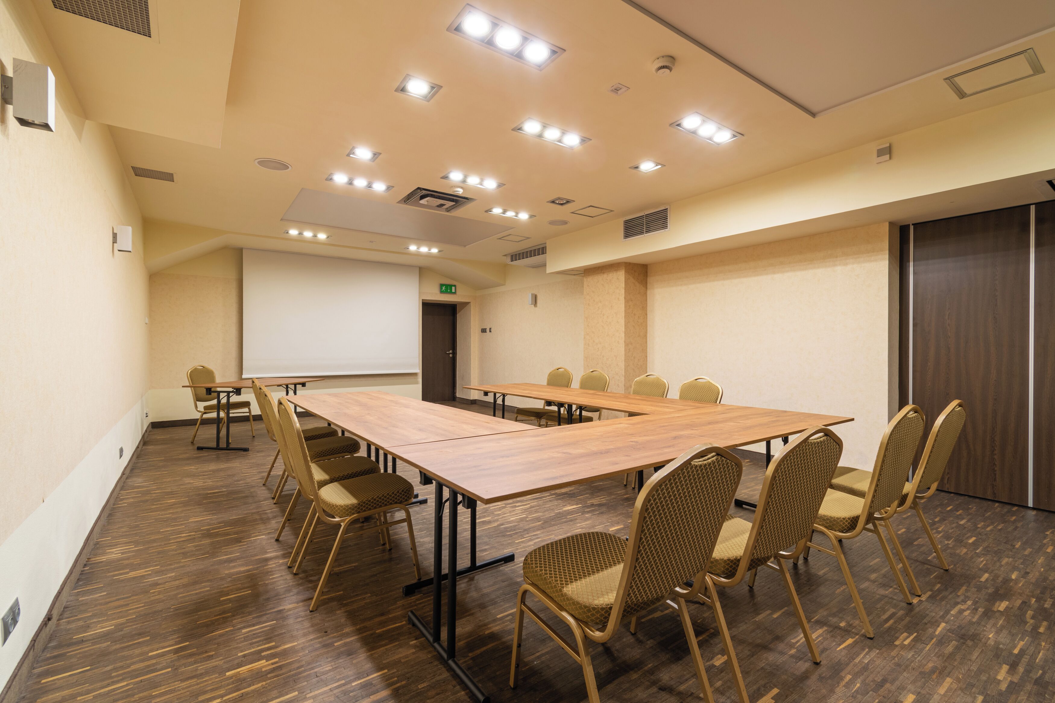 Uma sala de conferência com uma mesa comprida, cadeiras, um projetor e uma porta.