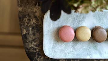 Uma mesa de mármore com um arranjo floral e três macarons.