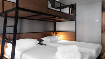 Quarto com beliche, cabeceira de madeira, duas camas, escada e luminária de cabeceira.