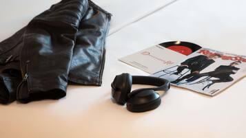 Uma jaqueta de couro preta, um par de fones de ouvido pretos e uma revista de Rolling Stones sobre uma superfície branca.