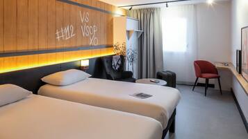 Quarto de hotel com duas camas, uma escrivaninha, uma cadeira vermelha e uma parede com painel de madeira e texto.