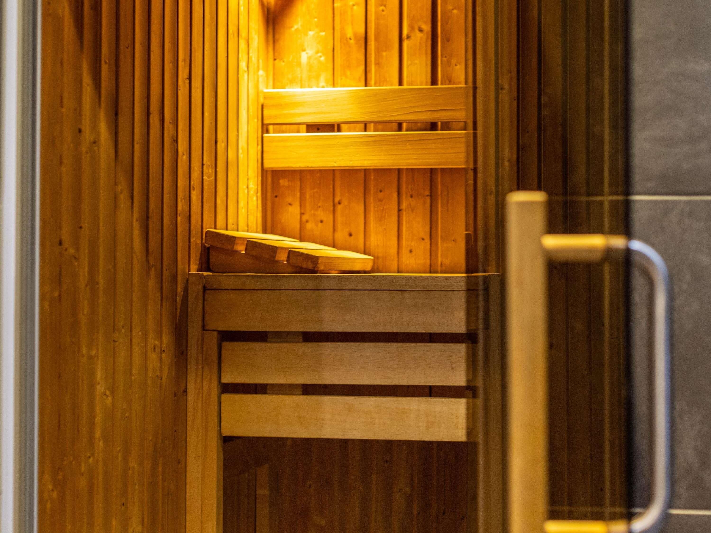 Uma sauna com bancos de madeira e porta de metal.