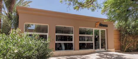 Um centro de fitness com grandes janelas e fachada bege.