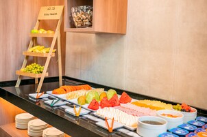 Buffet com diversas frutas, legumes e queijos.