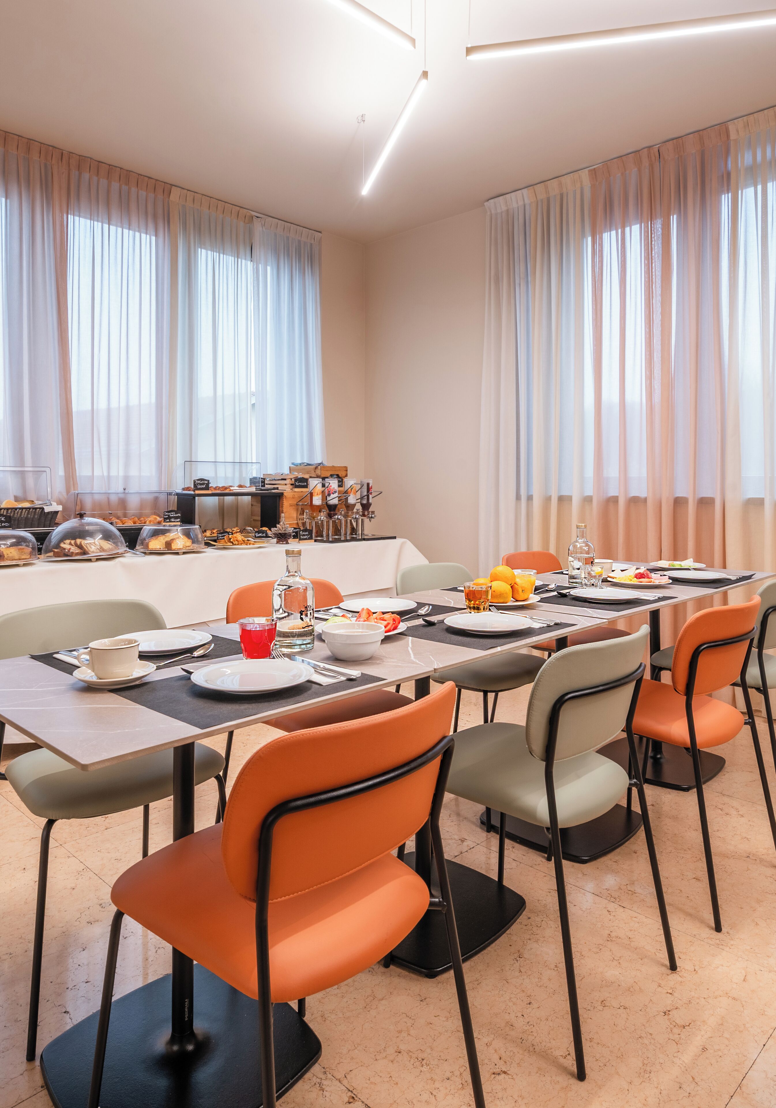 Uma sala de jantar com uma mesa comprida, cadeiras e itens de café da manhã.