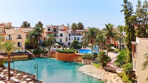 Um resort com piscina central, vários edifícios e palmeiras.