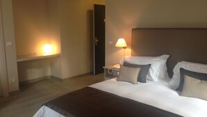 Quarto de hotel com uma cama grande, luminárias de cabeceira, um telefone e uma porta.