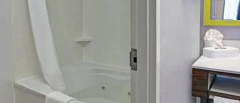 Um banheiro com banheira, vaso sanitário, pia e porta-toalhas.