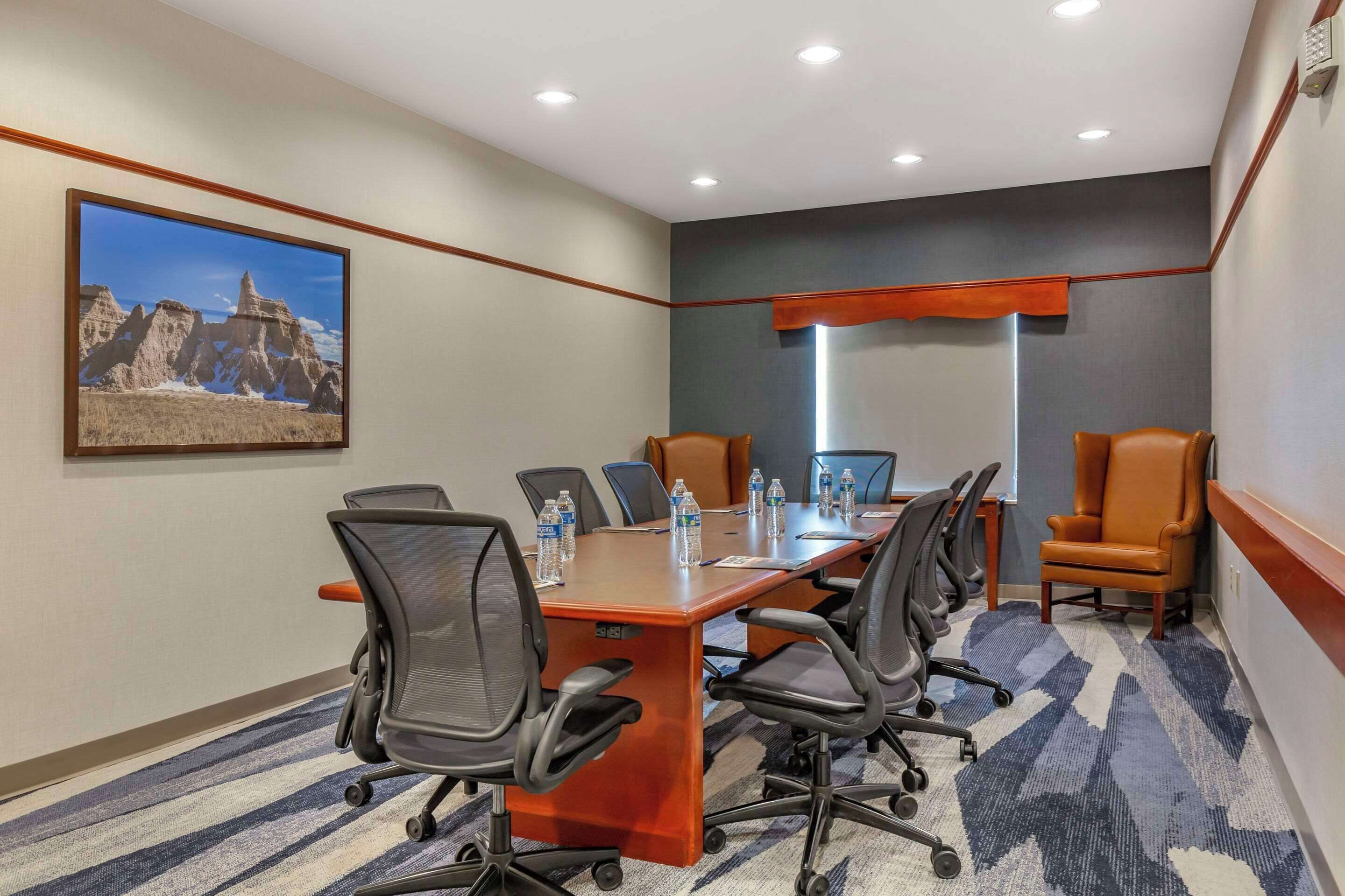 Uma sala de conferências com uma mesa comprida, cadeiras e um projetor.