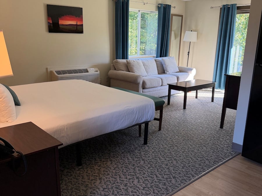 Quarto de hotel com cama, sofá, mesa e abajur.