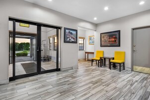 Um hall de hotel com design moderno, com piso de madeira, portas de vidro e quadros nas paredes.