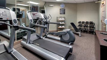 Centro de fitness com esteiras, máquinas de peso e halteres.