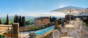 Um terraço com área de estar externa, piscina e vista para o campo.