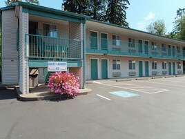Um motel com lavandaria para hóspedes, gelo e estacionamento, e uma fileira de quartos com varandas.