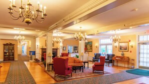 Um hall amplo com várias áreas de estar, lustres e um grande chão de madeira.