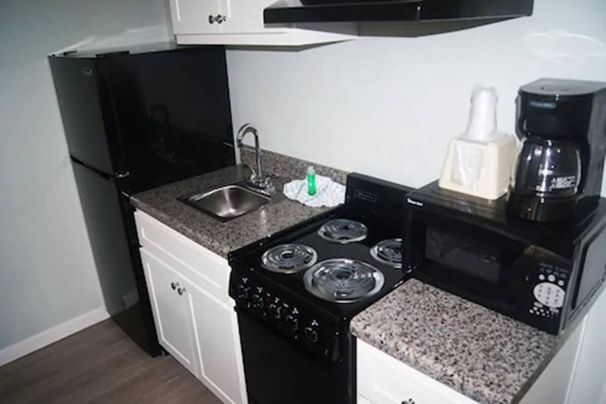 Cozinha compacta com fogão, pia e micro-ondas.