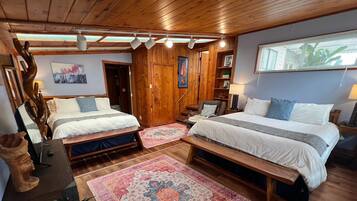 Um quarto acolhedor com duas camas, piso de madeira, claraboia e uma janela grande.