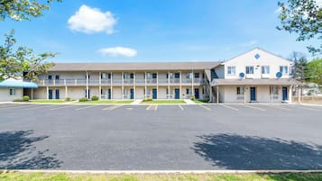 Um motel com estrutura de dois andares, estacionamento e antenas parabólicas no telhado.