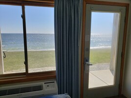 Quarto com vista para o mar através de uma janela, porta e ar condicionado fixado na parede.