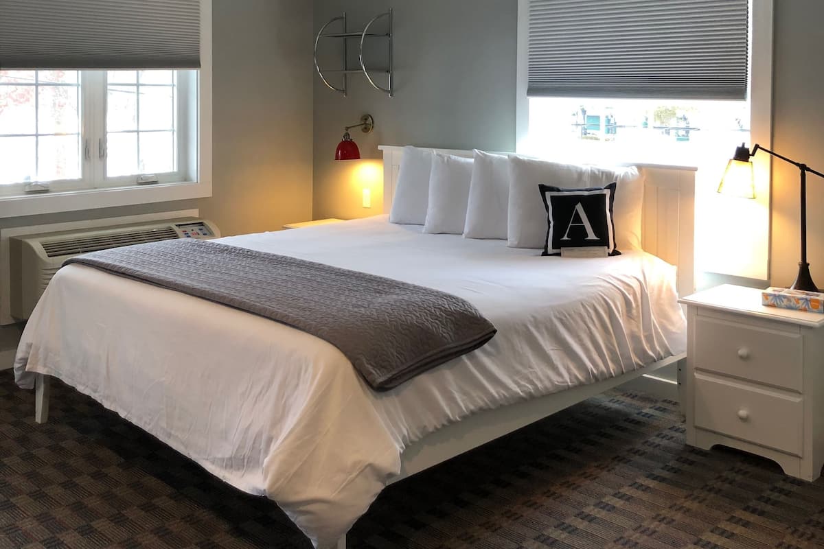Quarto bem arrumado com uma cama grande, mesas de cabeceira, um radiador e uma janela com persianas.