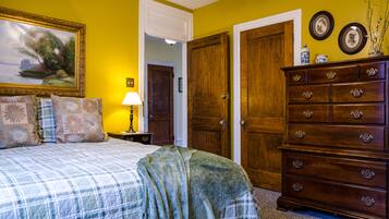 Um quarto com uma cama, uma cômoda, um quadro e uma porta que dá para outro espaço.
