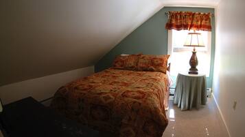 Quarto com uma cama, uma mesinha de cabeceira com abajur e uma janela com cortinas.