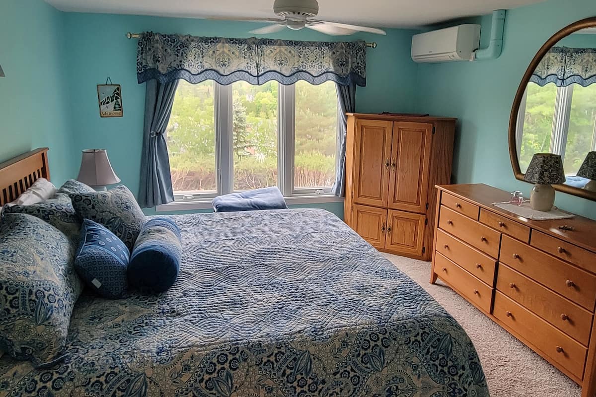 Quarto com cama, cômoda, guarda-roupa e ventilador de teto.