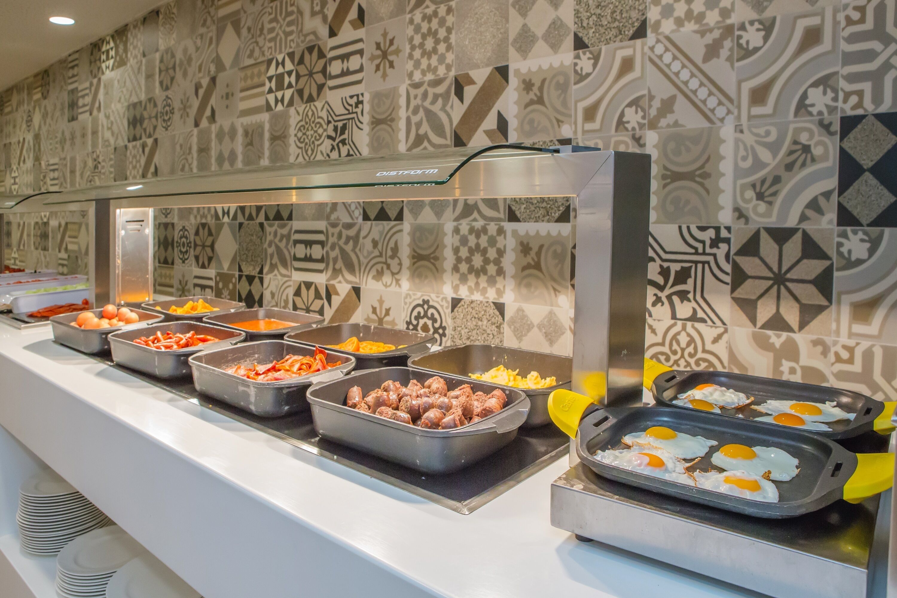 Buffet com diversos alimentos, incluindo ovos, linguiça e vegetais.