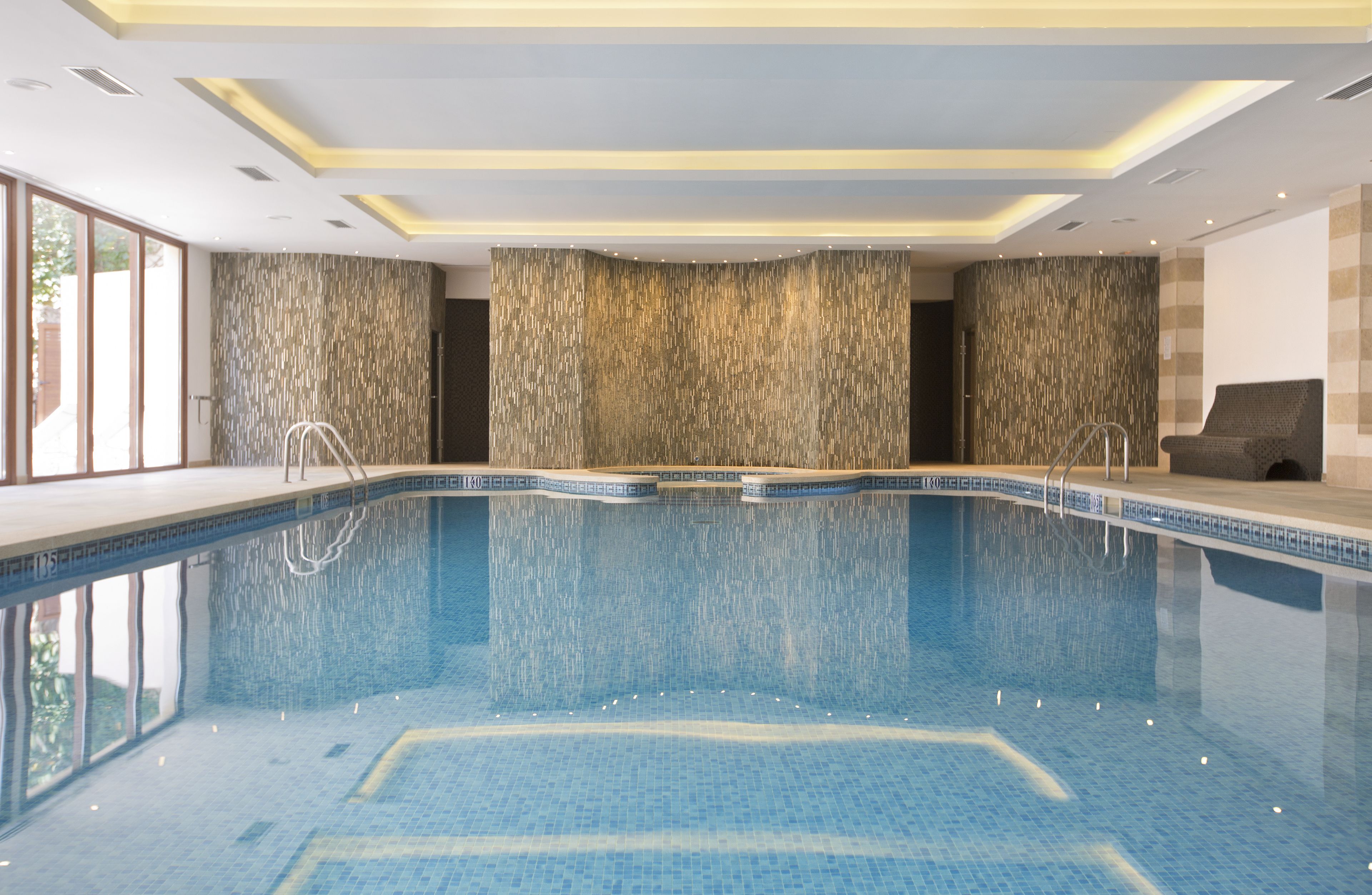 Uma piscina com superfície de água azul e límpida, rodeada por paredes com textura.