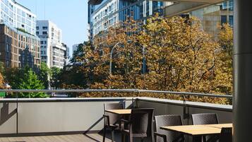 Varanda externa com vista para árvores de outono e edifícios modernos.