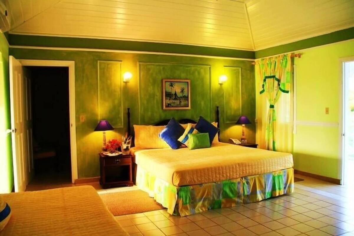Quarto com cama, mesas de cabeceira, um quadro e uma porta.
