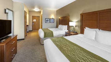 Quarto de hotel com duas camas, uma televisão, uma secretária e um abajur.