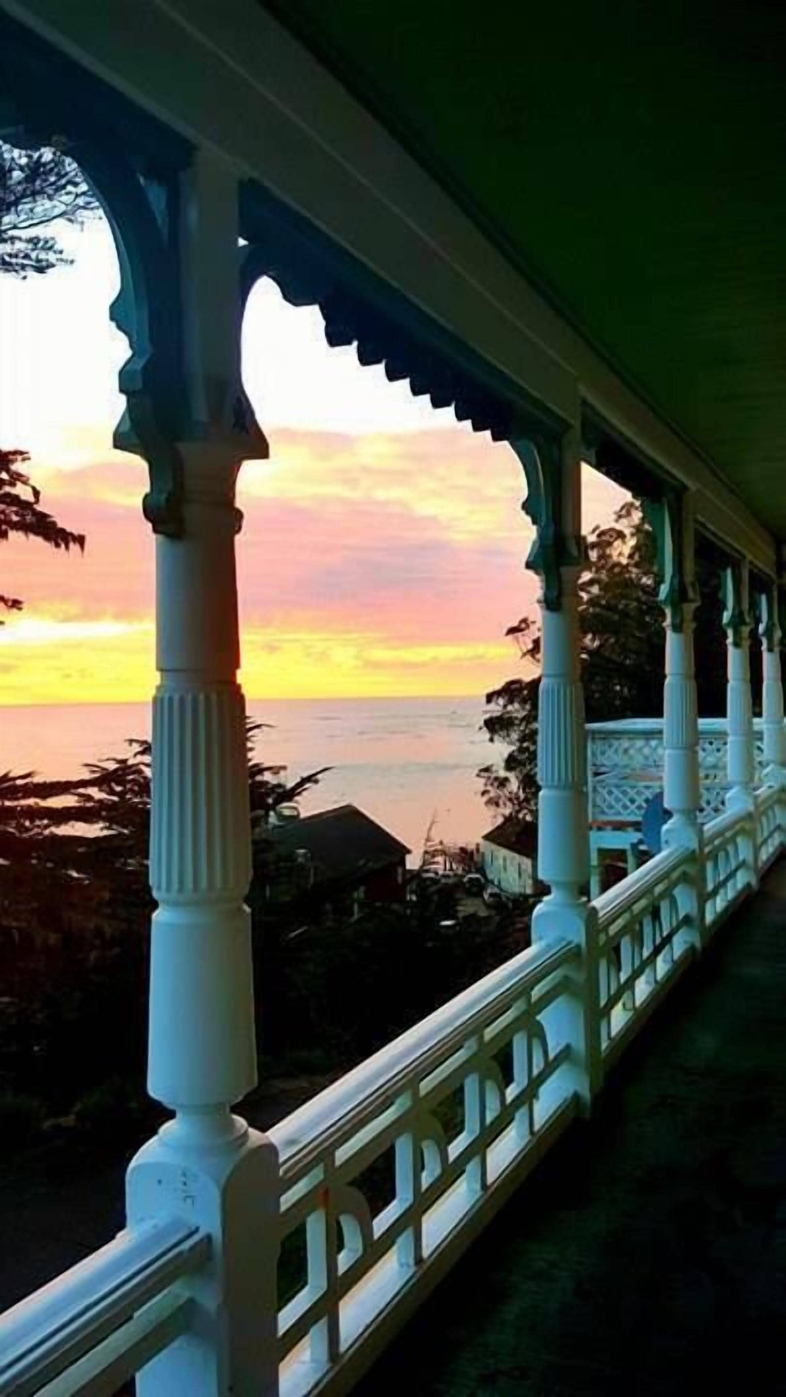 Uma varanda com vista para o pôr do sol sobre o mar.