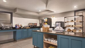 Cozinha moderna com armários azuis, uma ilha central com vitrine de vidro e diversos eletrodomésticos.
