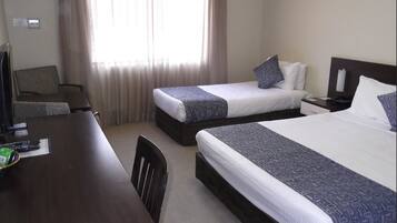 Quarto de hotel com duas camas, uma escrivaninha e uma televisão.
