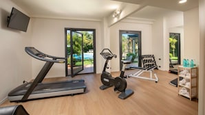 Uma academia em casa com esteira, elíptico e banco de musculação.