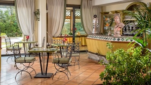 Restaurante com mesas ao ar livre, área de bar e vista para a vegetação.