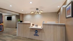 Uma mesa de recepção com o logotipo 'Best Western', uma luminária moderna e uma parede texturizada.