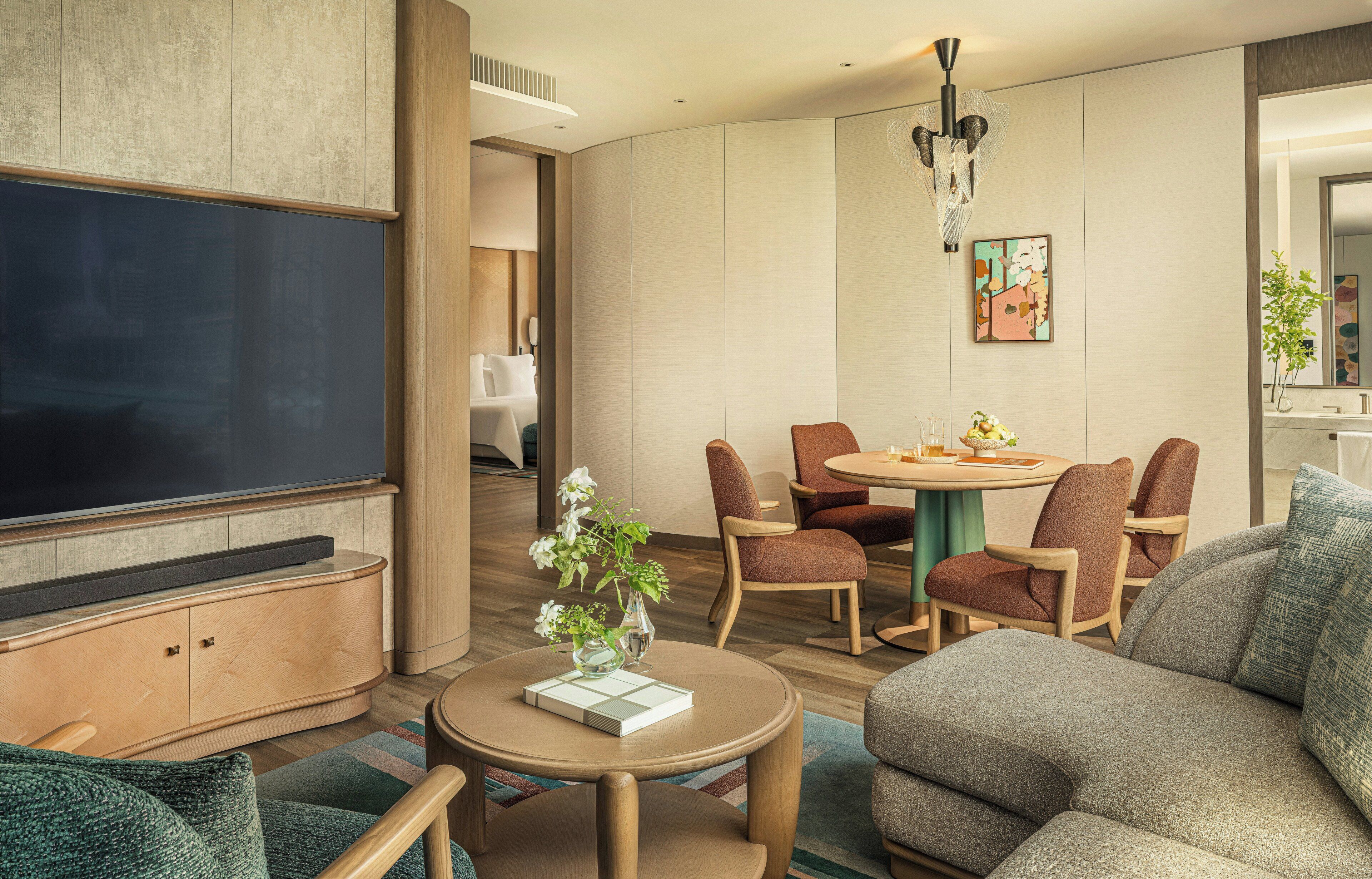 Uma sala de estar moderna com uma televisão de tela plana, uma mesa de jantar com cadeiras, um sofá e um vaso decorativo.