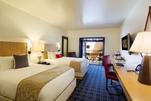 Quarto de hotel com duas camas, uma escrivaninha com telefone e uma cadeira.