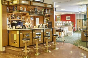 Uma área de bar com banquetas, balcão e prateleiras com garrafas.
